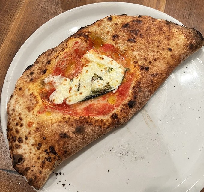 Not just a calzone, but a golden-brown masterpiece with a crackling exterior that gives way to molten cheese and savory fillings. Pizza's sophisticated cousin.