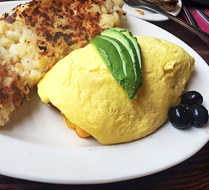 That's not just an omelet – it's a fluffy yellow cloud of perfection with perfectly crispy hash browns. The avocado adds that quintessential California touch.
