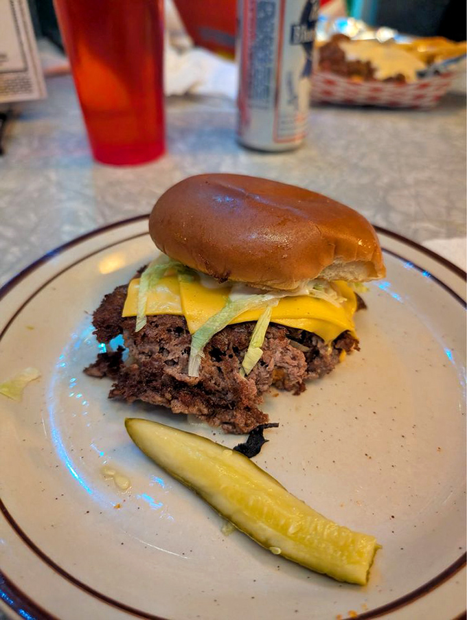 This isn't just a burger&mdash;it's edible architecture with crispy-edged beef, melty cheese, and a pickle sidekick.