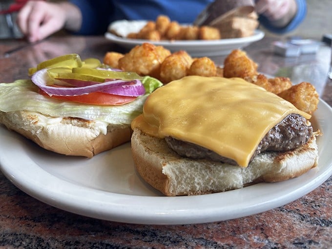 This isn't just a cheeseburger &ndash; it's therapy on a plate, complete with perfectly golden tater tots that crunch like autumn leaves underfoot.