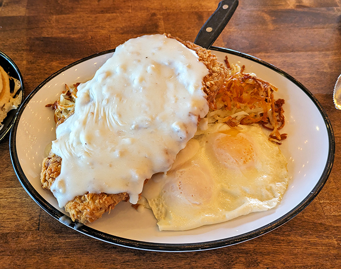Behold the crown jewel: chicken fried steak swimming in peppery cream gravy alongside golden hash browns and sunny-side-up eggs.