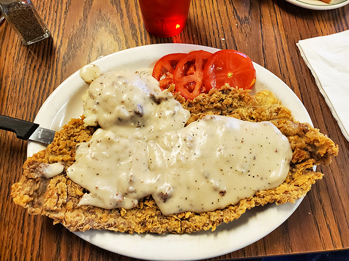 Behold the star attraction: chicken fried steak draped in pepper-flecked gravy that cascades like a savory waterfall. This isn't a meal; it's a religious experience.