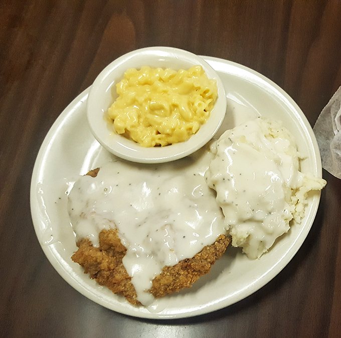 Golden-crusted chicken fried steak drowning in creamy gravy alongside fluffy mashed potatoes - pure heaven.