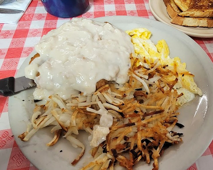 Behold the holy trinity of breakfast perfection: crispy hash browns, creamy gravy, and eggs that somehow manage to be both fluffy and substantial at once.