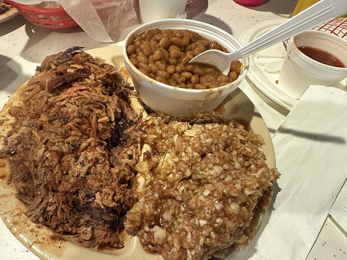 Barbecue nirvana on a plate: chopped pork with that signature pink smoke ring, baked beans, and red slaw&mdash;a holy trinity of Southern comfort.