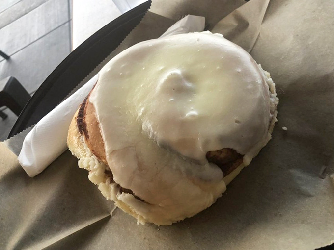 Behold, the crown jewel: a cinnamon roll that makes time stand still. That cream cheese frosting practically demands you lick the paper afterward.