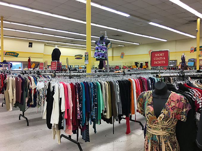 Color-coded clothing racks stretch toward the horizon, a textile rainbow promising fashion gold at the end.