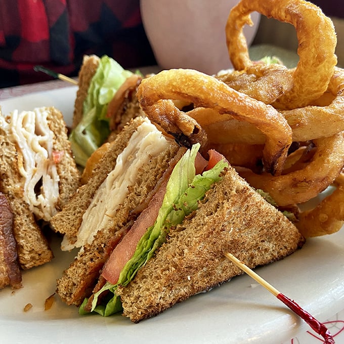 The legendary club sandwich that launched a thousand road trips. Those perfectly golden onion rings aren't just sides&mdash;they're supporting characters in a delicious drama.