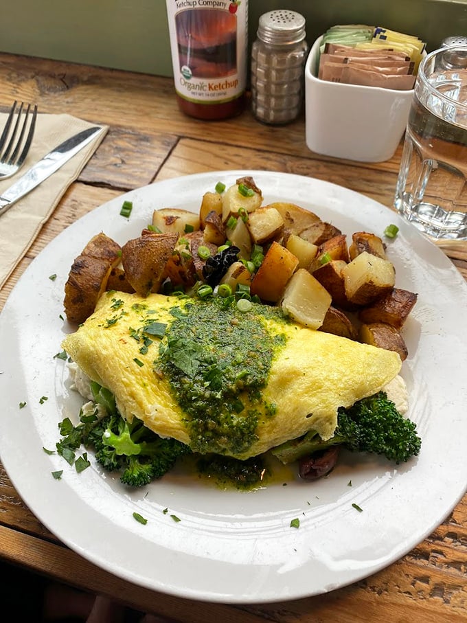 Behold the omelet that launched a thousand road trips. Those crispy potatoes deserve their own fan club, while that vibrant green sauce whispers, "You're welcome."