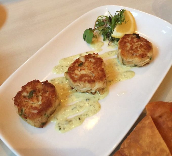 Three golden rounds of perfection sitting in sauce that knows its supporting role&mdash;this is crab cake artistry at work.