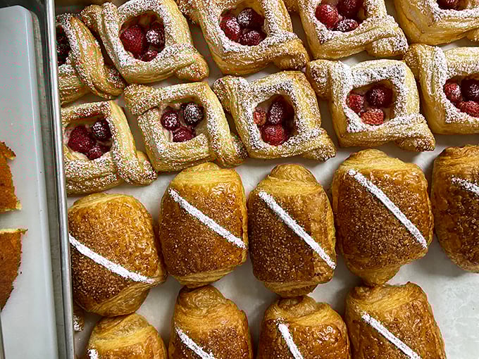 These berry-topped pastries and golden croissants aren't just breakfast—they're edible architecture with powdered sugar snow dusting the rooftops.