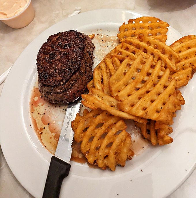 Behold the star of the show: a perfectly seared filet mignon alongside golden waffle fries. Meat this tender doesn't need a knife&mdash;just a moment of silent appreciation.