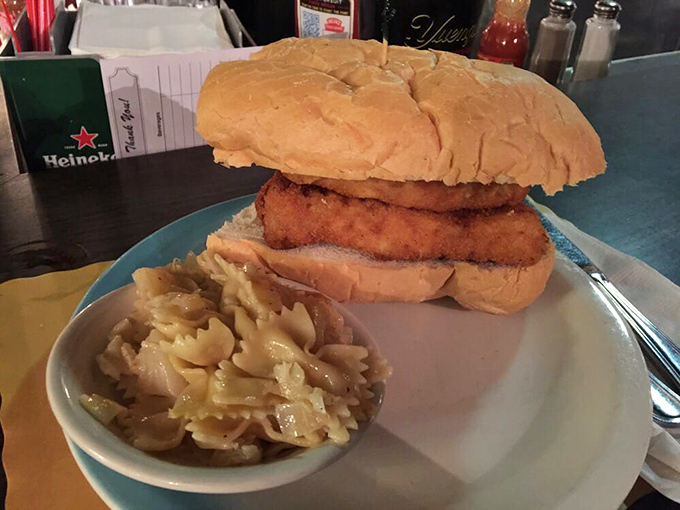 Behold the legendary fish sandwich in all its glory &ndash; architectural marvel meets culinary masterpiece, with pasta salad playing a humble supporting role.