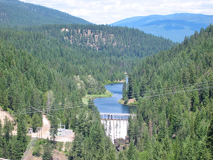 The Moyie Dam creates a serene blue mirror above the falls, proving that even water likes to catch its breath before the big plunge.