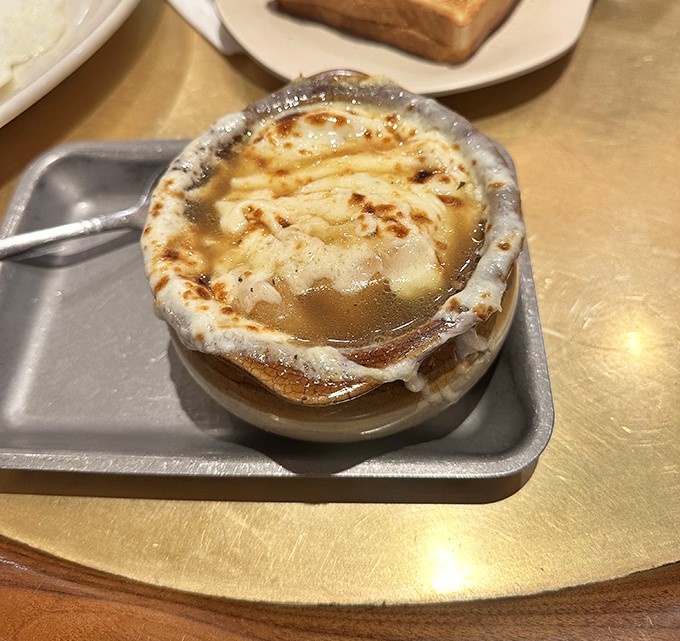 The French onion soup arrives like a geological marvel—layers of molten cheese concealing a rich, savory broth that could make a Frenchman weep with joy.