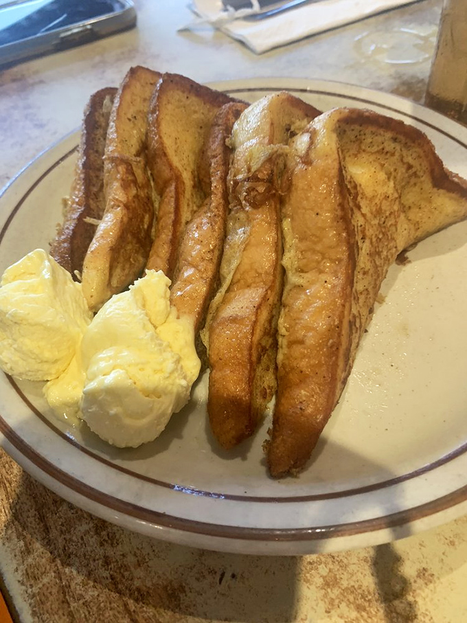 Golden-brown French toast stacked high with a side of butter &ndash; breakfast architecture that would make Frank Lloyd Wright proud.
