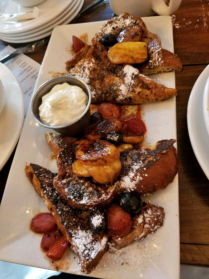 French toast nirvana exists! Thick-cut brioche dusted with powdered sugar and crowned with caramelized fruits creates that perfect crispy-outside, custardy-inside magic.