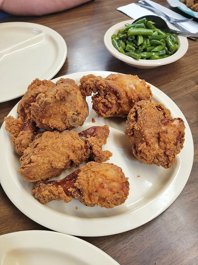 Golden-brown perfection on a plate. This isn't just fried chicken – it's edible history, served with a side of green beans for good measure.