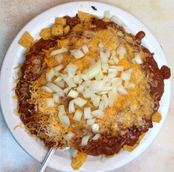 This Frito Pie isn't just a dish&mdash;it's an architectural marvel of corn chips, chili, cheese, and diced onions that demands both a fork and respect.
