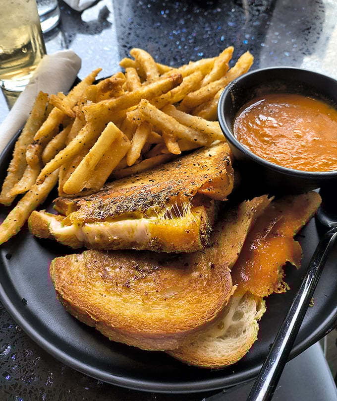 Behold the holy grail of comfort food—golden-brown perfection with molten cheese spilling out, accompanied by crispy fries and tomato soup for dipping.