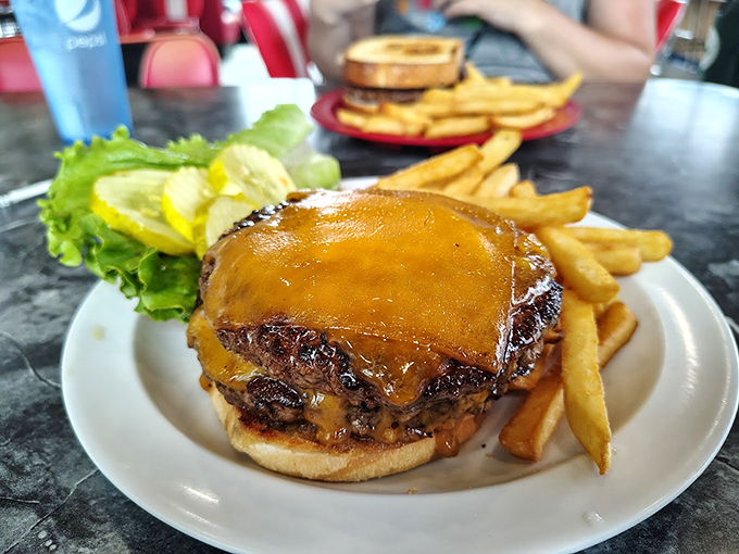 Behold the star attraction: a half-pound burger that doesn't just satisfy hunger&mdash;it obliterates it. That melted cheese cascading down the sides isn't an accident; it's edible architecture.