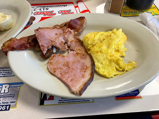 The legendary ham steak arrives like a carnivore's dream—thick, caramelized at the edges, and paired with eggs that know their supporting role.