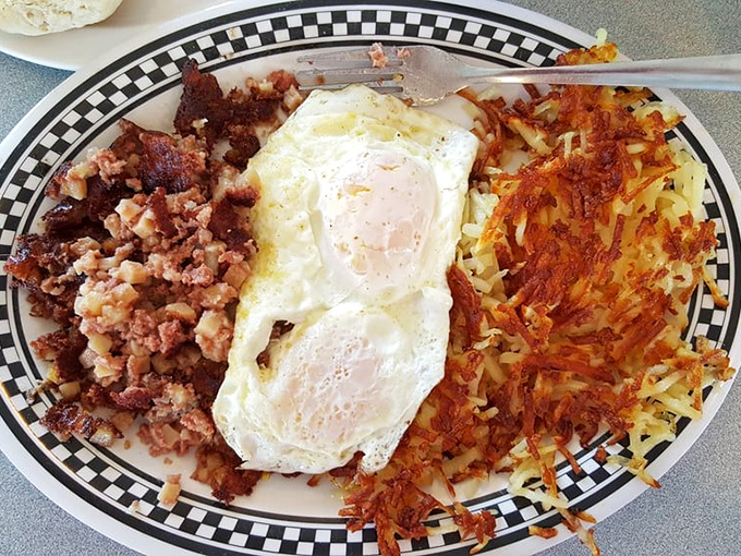 Corned beef hash, sunny-side-up eggs, and crispy hash browns &ndash; the holy trinity of breakfast perfection on a classic checkered plate.