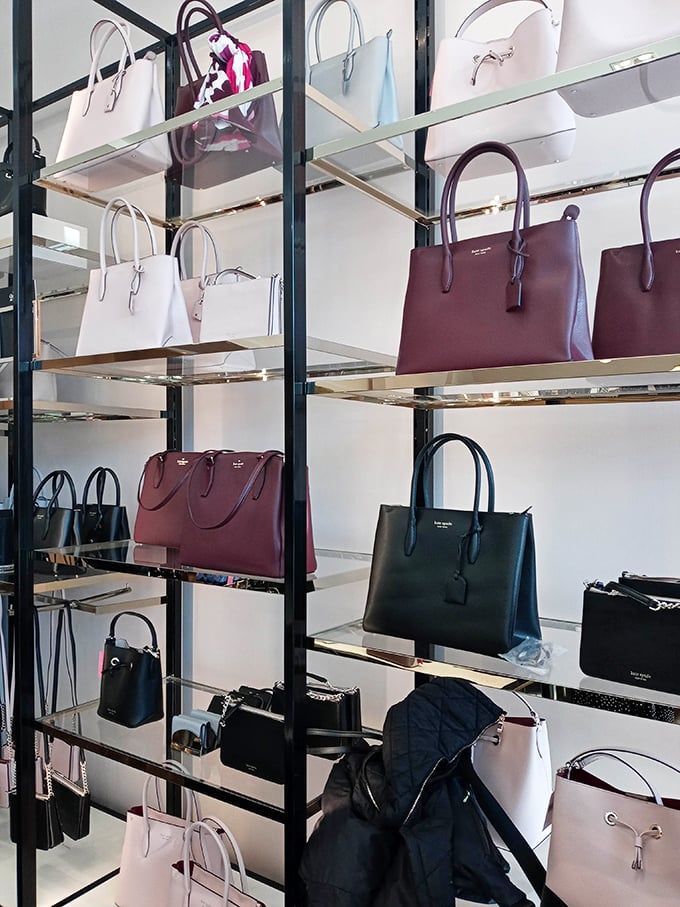 Kate Spade's rainbow of handbags displayed like precious gems, each one whispering "you need me" in expensive leather.