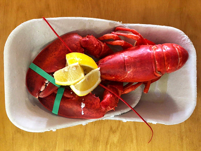 A bright red lobster lounges in its paper boat like it's at a seafood spa. Those lemon wedges aren't garnish&mdash;they're the perfect citrus dance partners.