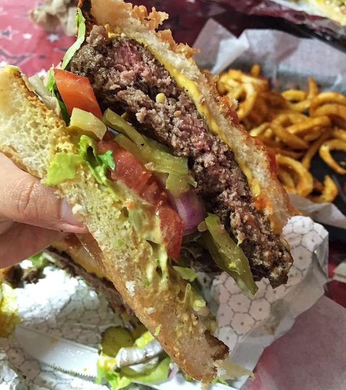 This isn't just a burger; it's edible architecture. Each layer perfectly balanced between bun borders, with a patty cooked to juicy perfection.