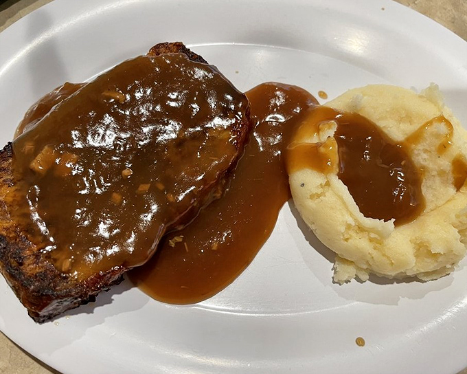 Behold the star attraction: meatloaf swimming in rich brown gravy alongside cloud-like mashed potatoes. This isn't just dinner&mdash;it's edible nostalgia that makes you want to call your mother.
