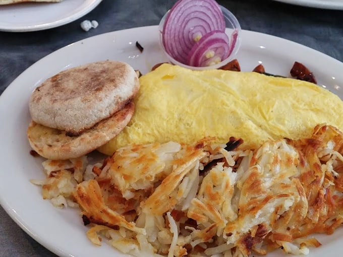 Breakfast perfection on a plate: golden omelet, crispy hash browns, and an English muffin. That red onion garnish isn't just for show&mdash;it's the exclamation point on a perfect sentence.