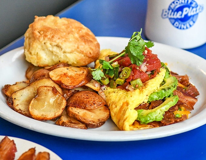 This isn't just an omelet; it's a masterpiece of fluffy eggs embracing fresh ingredients. Those crispy potatoes and homemade biscuit are the perfect supporting cast.