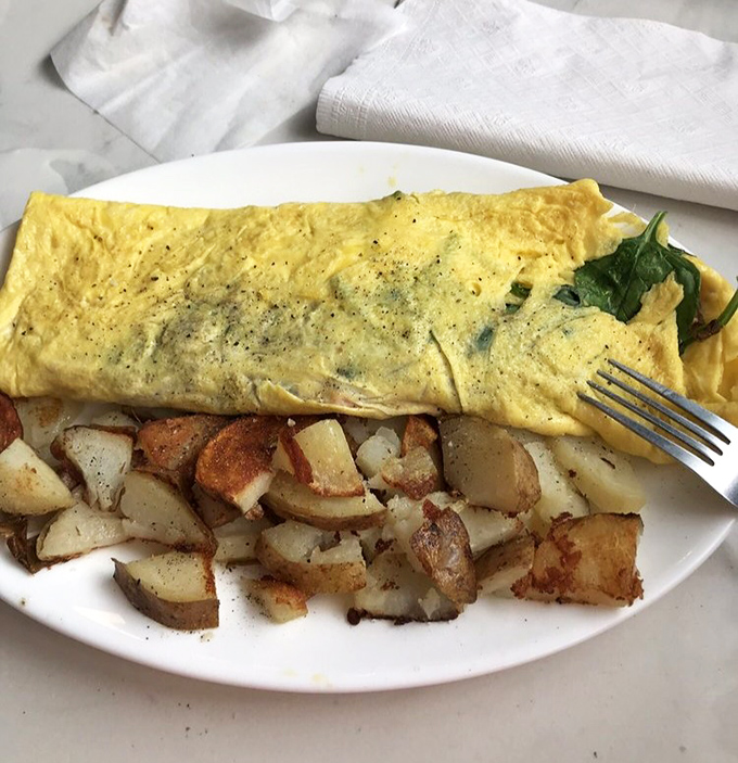 This isn't just an omelet&mdash;it's a golden-hued masterpiece of egg perfection, paired with home fries that could make a potato farmer weep with pride.