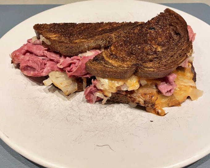 Behold the Reuben in all its marble rye glory—corned beef and sauerkraut performing a perfect tango of flavors that would make competitive dancers jealous.