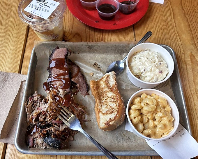 A metal tray of barbecue bliss: pulled pork, brisket, creamy mac and cheese, and Texas toast ready for their close-up.