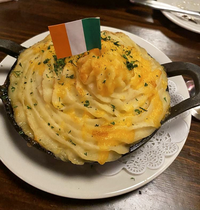 Behold the star attraction: shepherd's pie crowned with a golden potato peak and tiny Irish flag, like a delicious mountain that's claimed its sovereignty on your plate.