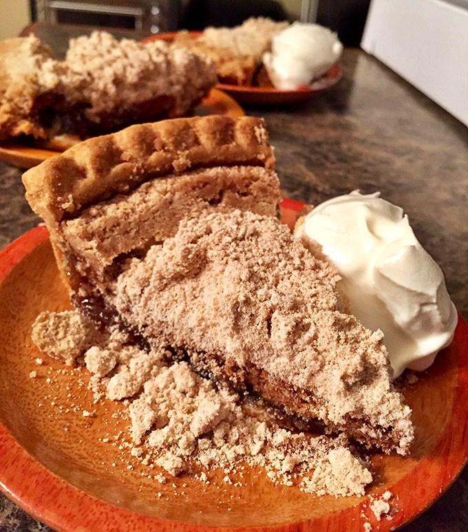Behold the star of the show: wet-bottom shoo-fly pie with a dollop of whipped cream, where molasses meets crumb topping in perfect, sweet harmony.