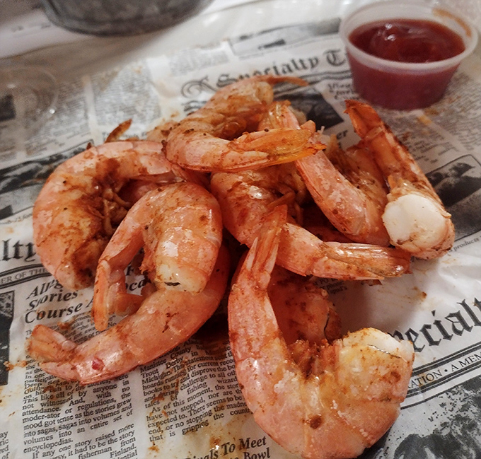 These steamed shrimp aren't just food; they're little pink promises of happiness, served newspaper-style with no pretension.