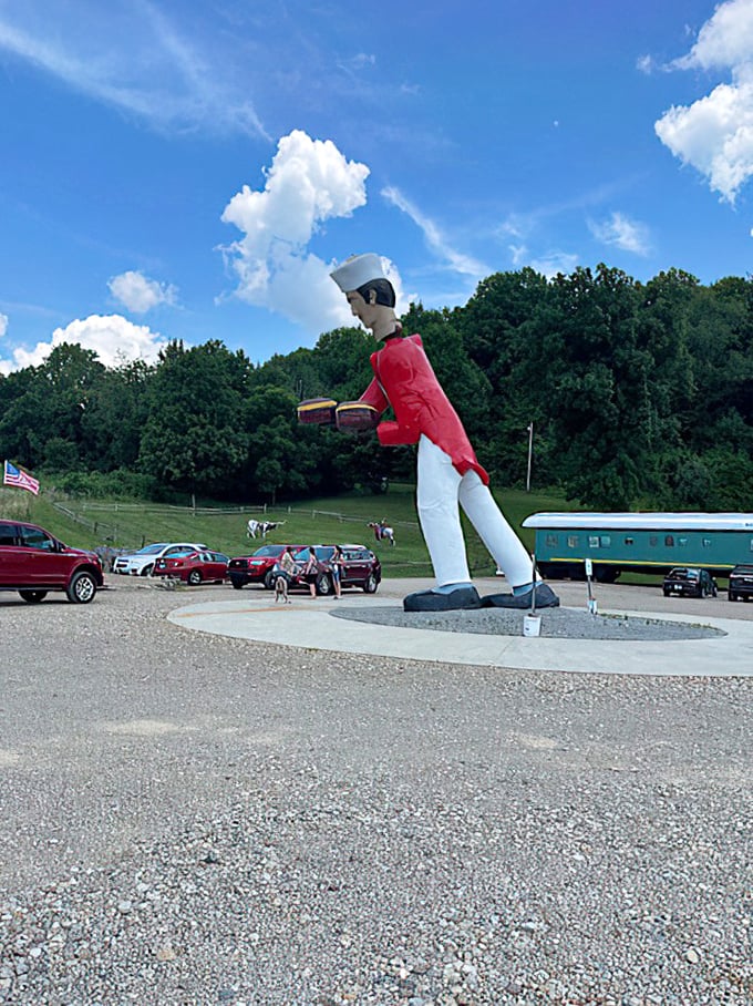 Even on cloudy days, the chef's vibrant red jacket stands out like a beacon. His perpetual lean suggests he's eager to greet every passing traveler.