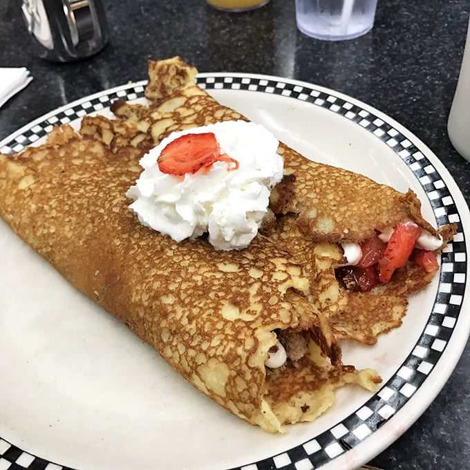 Behold the famous crepe-style hotcake in its natural habitat &ndash; golden-brown, crispy-edged, and stuffed with strawberry treasure. That whipped cream crown is well-deserved royalty.