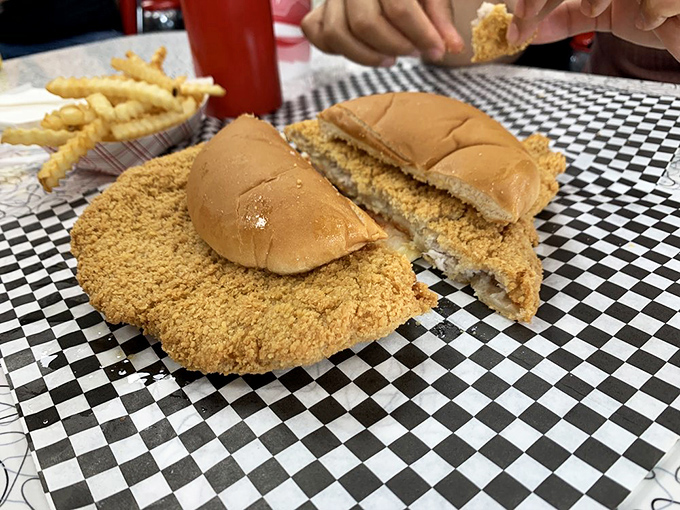 The Iowa state flower: a golden-brown tenderloin blooming beyond its bun. This sandwich requires both hands, strategic planning, and zero shame.