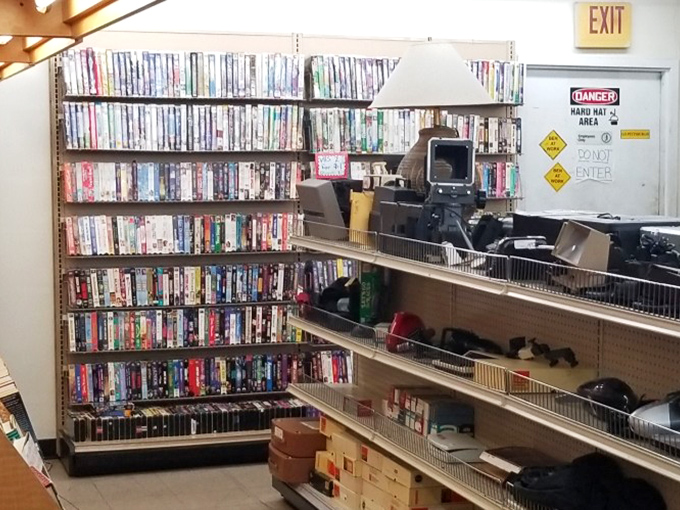 VHS tapes and electronics create a time capsule effect. Remember when choosing a movie meant wandering aisles instead of scrolling endlessly through streaming options?