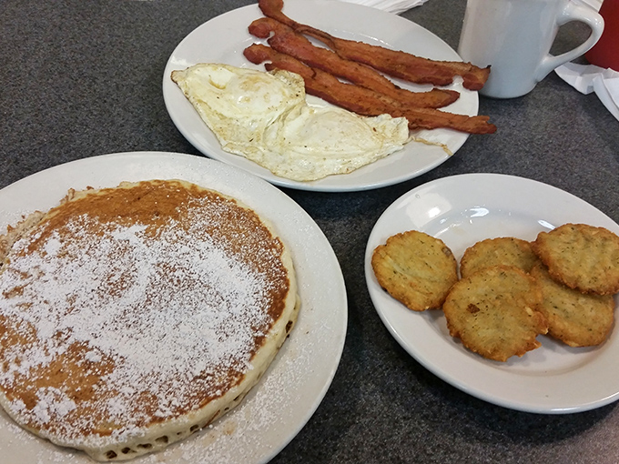 Fluffy pancakes dusted with powdered sugar, crispy bacon standing at attention, and eggs cooked exactly right&mdash;breakfast perfection on three plates.