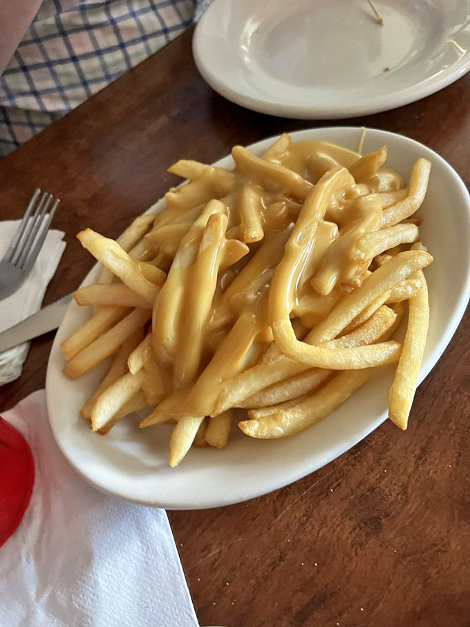 Golden fries swimming in cheese sauce—a simple pleasure that somehow tastes better here than anywhere your passport has taken you.