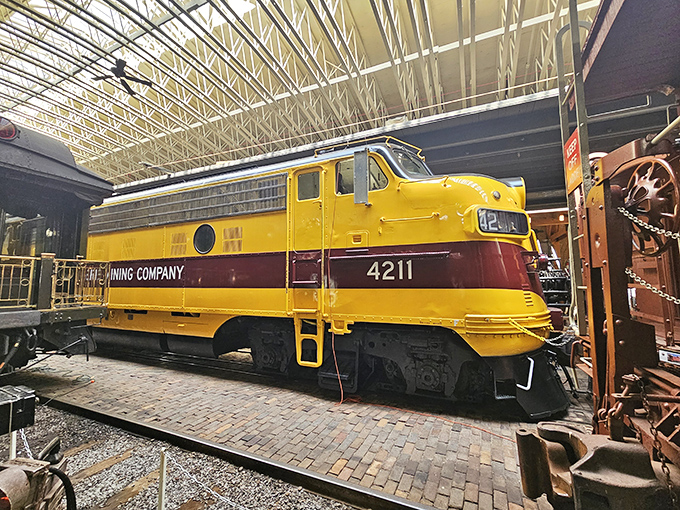 The vibrant yellow Duluth, Missabe & Iron Range diesel locomotive #4211 gleams under museum lights, a sunshine-colored giant from railroading's diesel revolution.