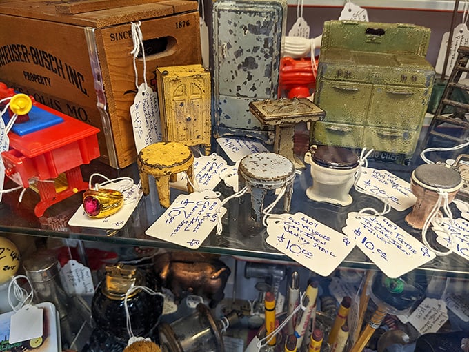 Tiny cast iron treasures with handwritten price tags tell stories bigger than their size. Each miniature toilet and safe holds outsized charm.