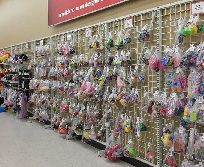 Plastic bags filled with toy collections hang like colorful fruit, each containing potential childhood magic at secondhand prices.