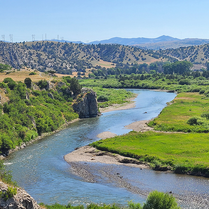 The river curves through the landscape like nature's signature, a blue autograph on Montana's vast green canvas.