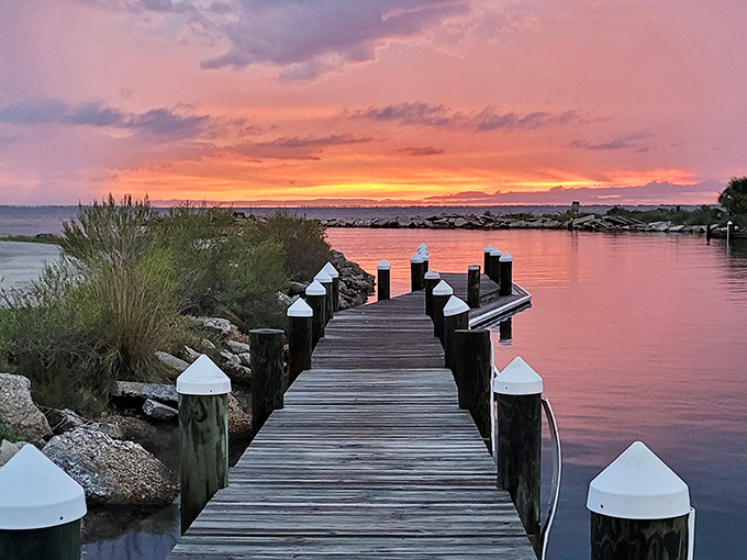 Nature's nightly masterpiece unfolds over a weathered dock, where the sunset transforms ordinary wood planks into front-row seats to heaven's light show.